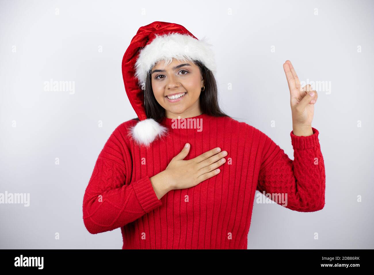 Young beautiful woman wearing a Santa hat over white background smiling ...