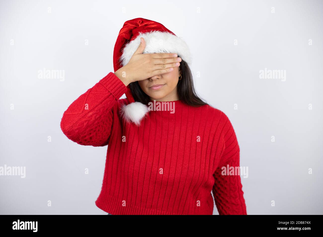 Young beautiful woman wearing a Santa hat over white background serious ...