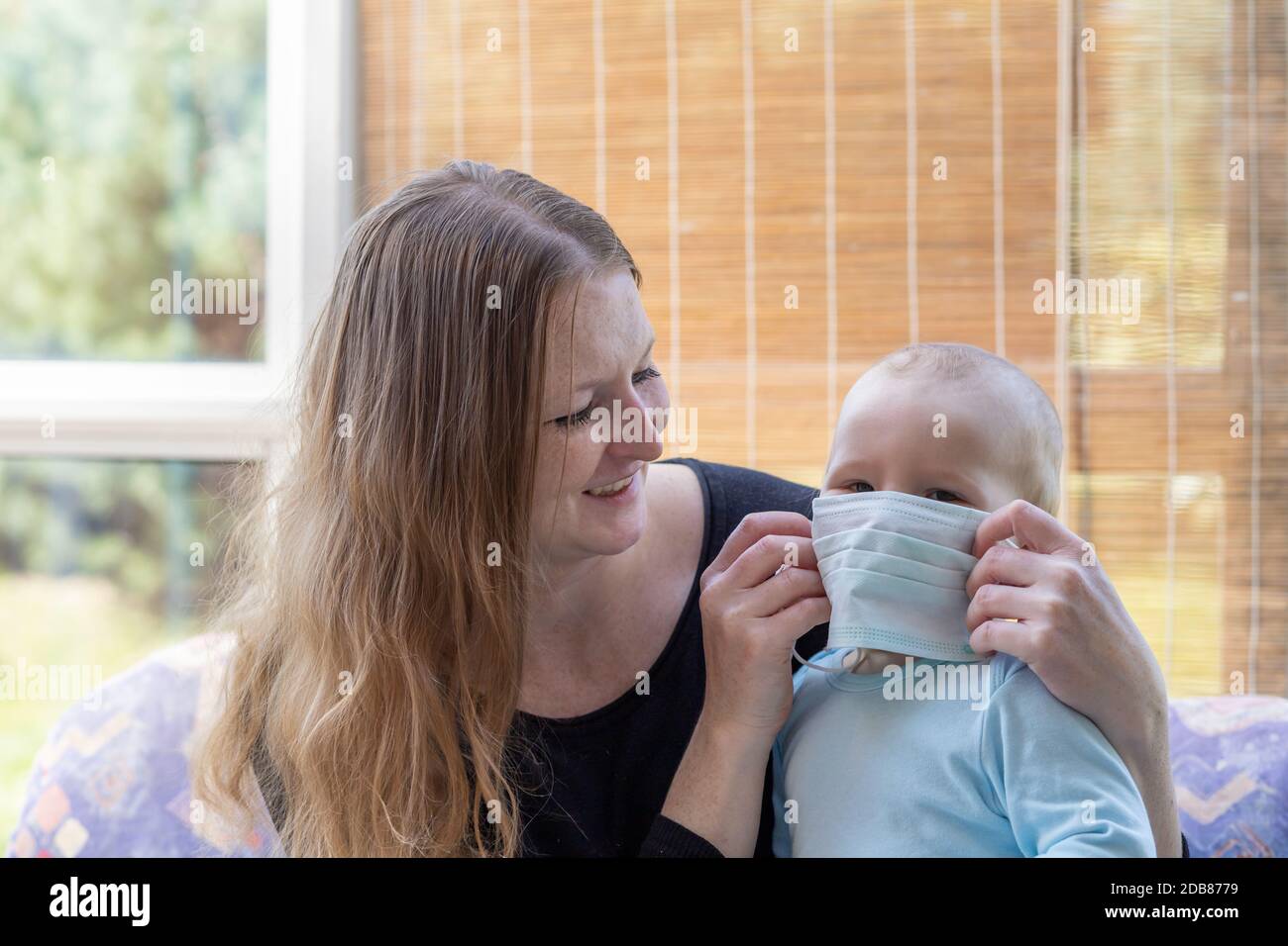 Smiling mom and her little son with disposable protective mask on his ...