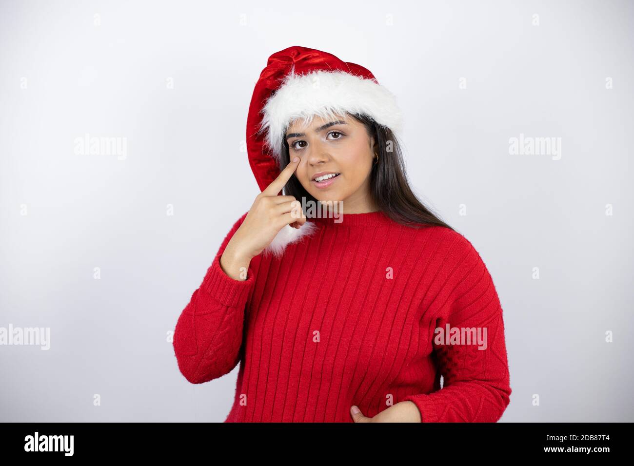 Young beautiful woman wearing a Santa hat over white background ...