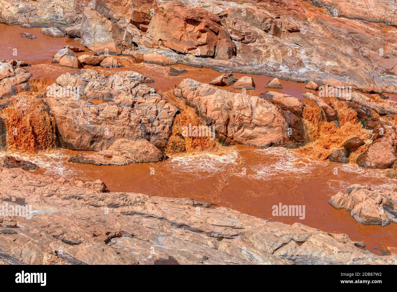 Rocky river bed Betsiboka river after heavy rain, fast red yellow water ...