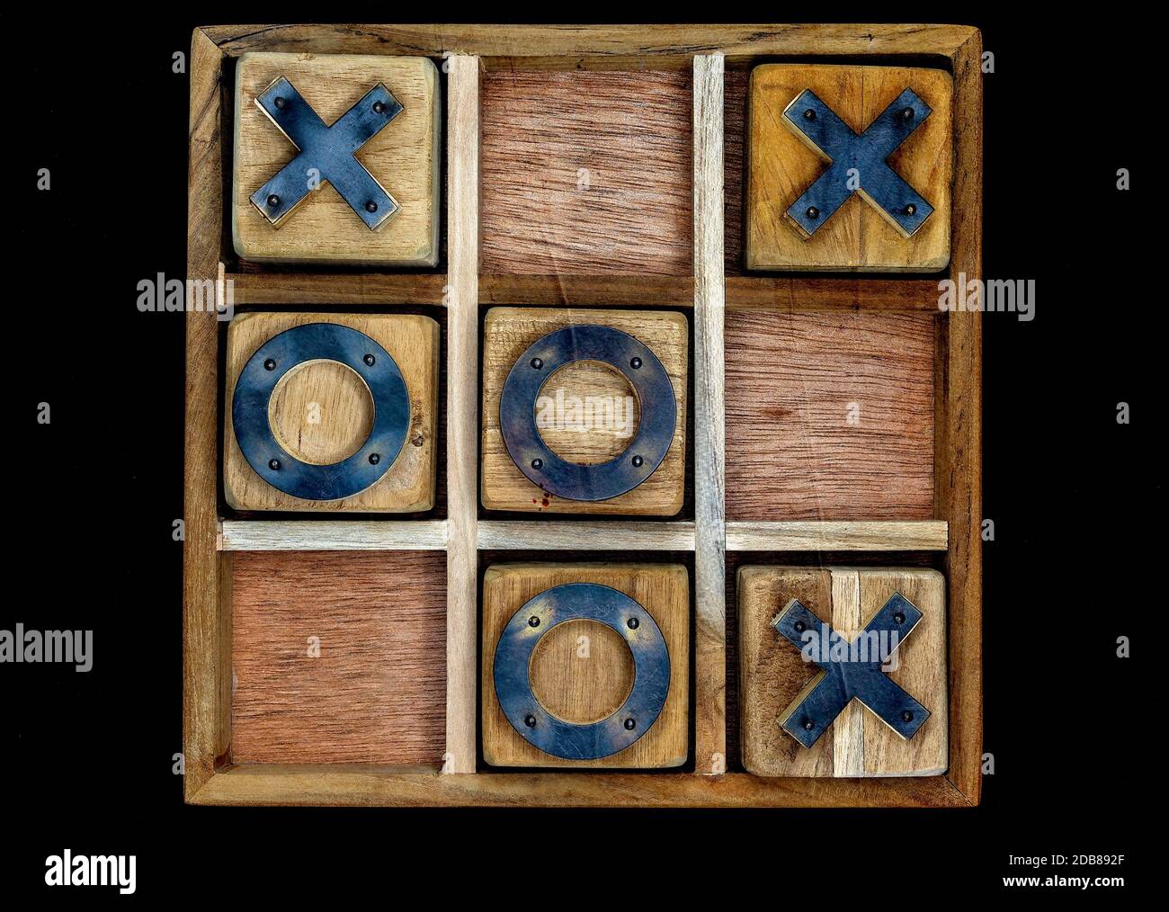 A wooden game set of noughts and crosses on a black background, also ...