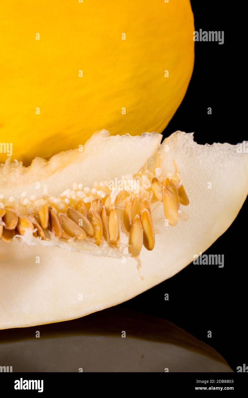 Big single whole and cut fruit of yellow honey melon isolated on black ...