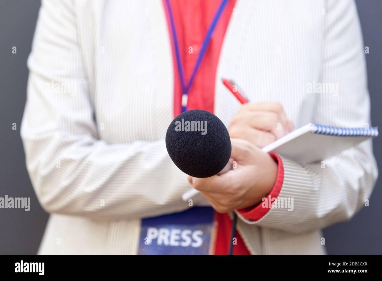 Female reporter at press conference, writing notes, holding microphone ...