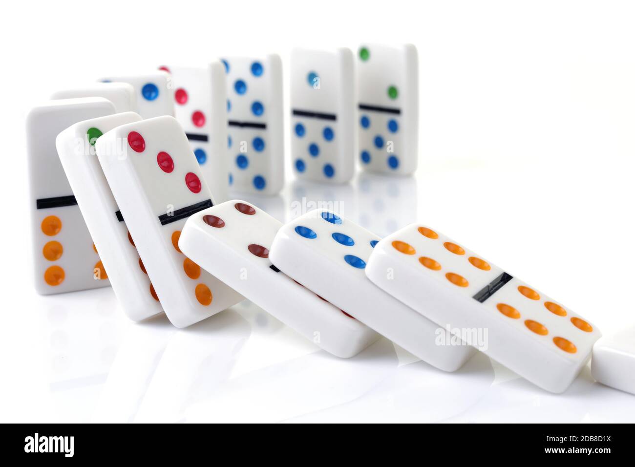 A line of falling colorful dominoes on a white surface Stock Photo - Alamy