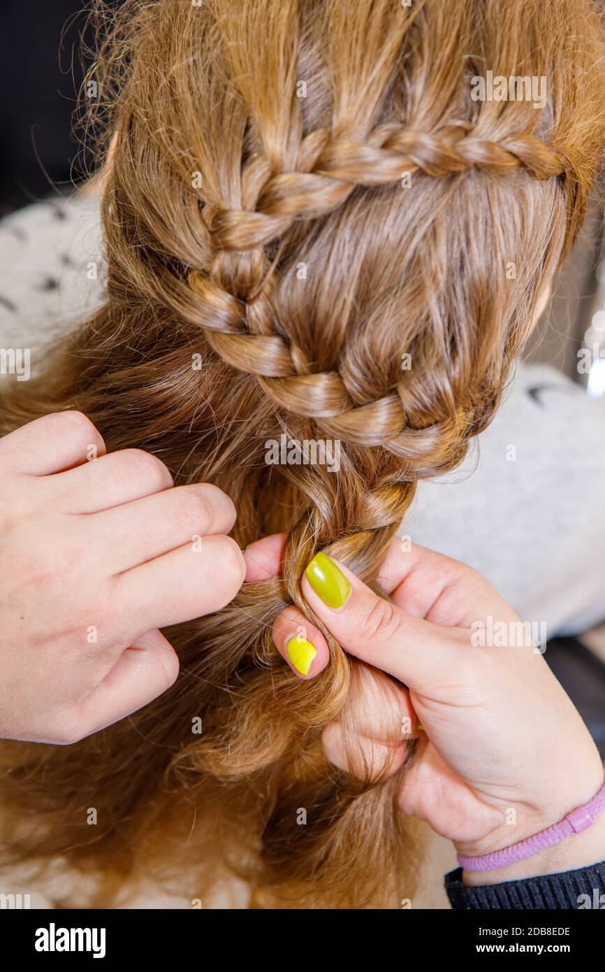 Professional braiding of braids by a master hairdresser in a beauty ...