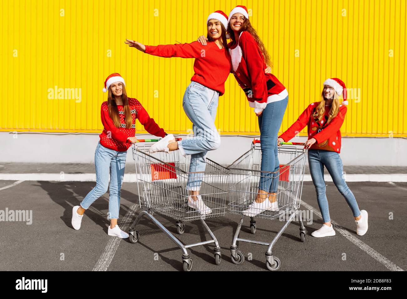 Group of four young women in Christmas sweaters and Santa Claus hats ...