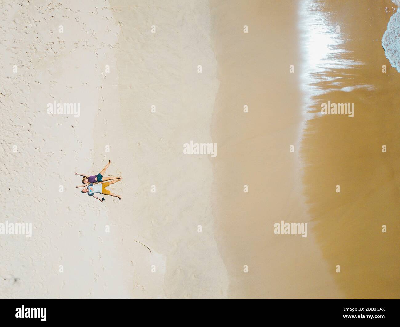 A couple is having fun and making sand angels on the beach in Australia ...