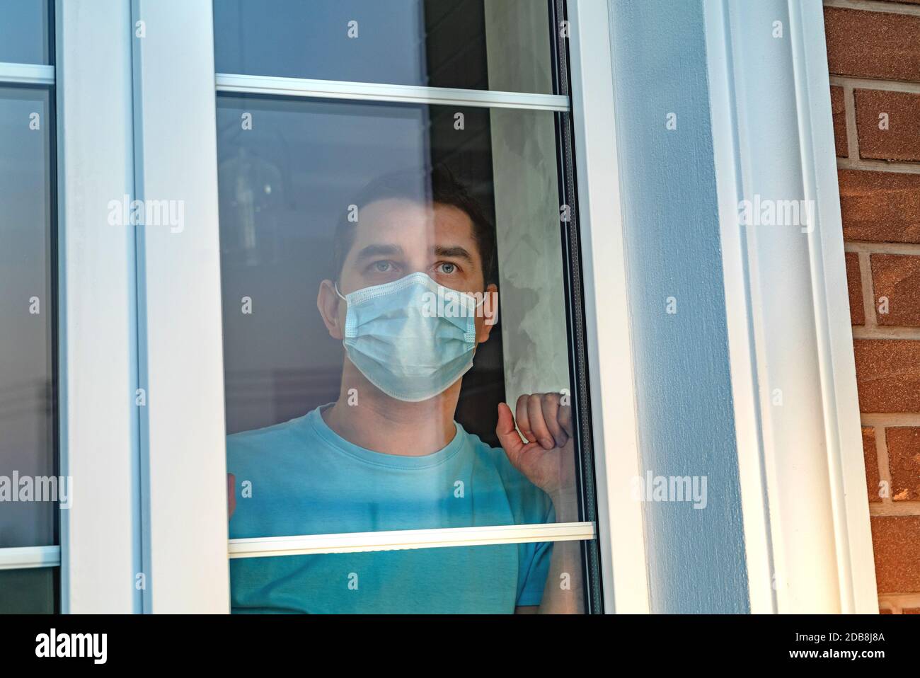 Infected man on self-isolation looks at street through the window of a ...