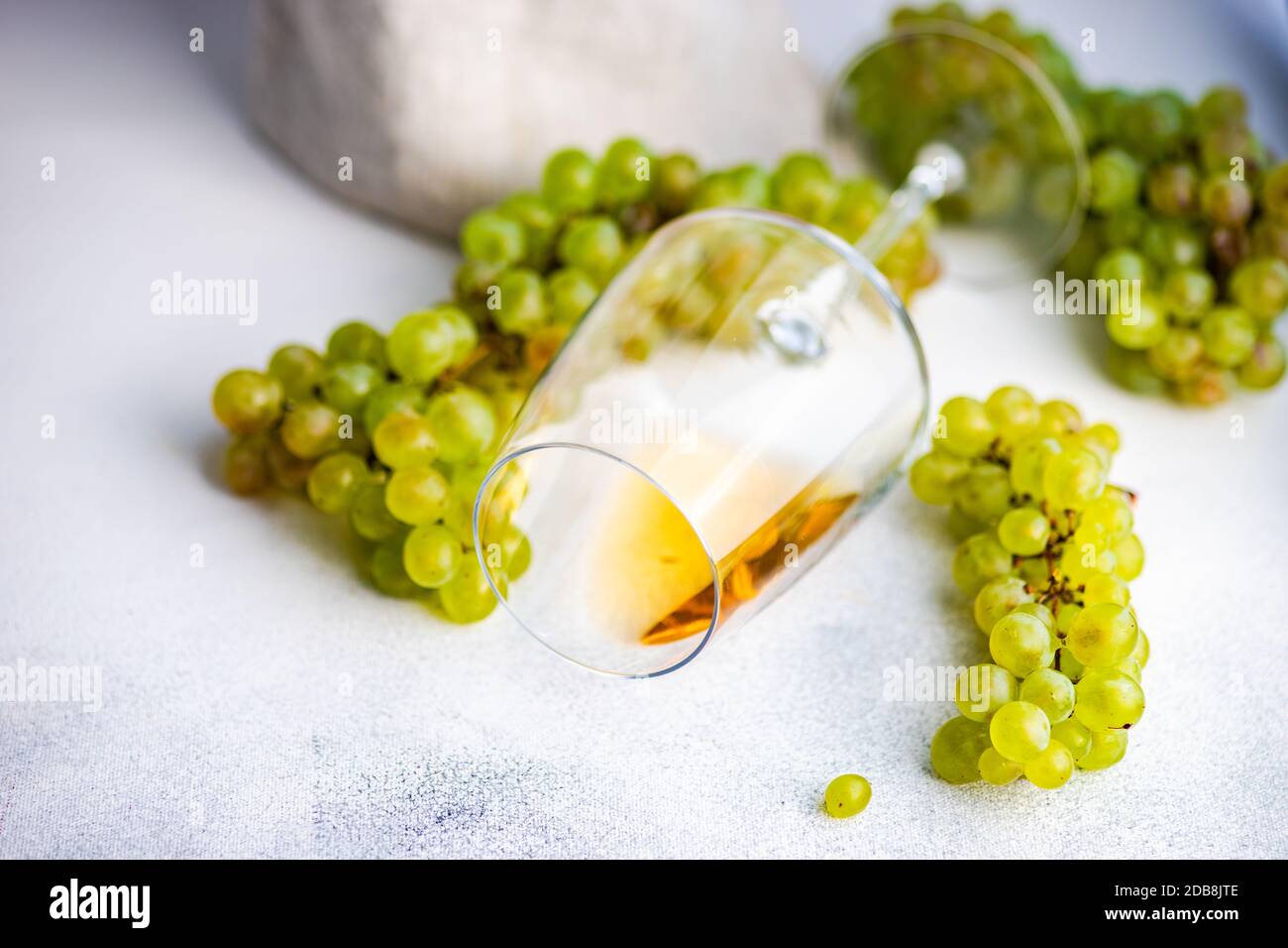 Spilled glass of white wine lying next to green grapes on a table Stock ...