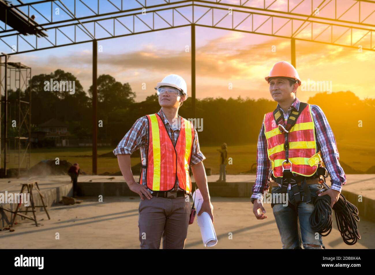 Two engineers looking at building plans on a construction site ...