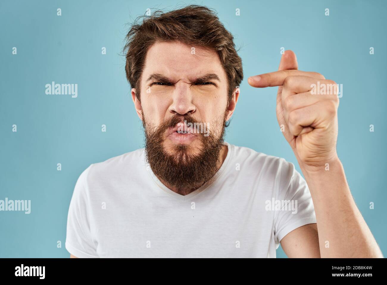 Bearded man in white T-shirt emotions gestures with hands displeased ...