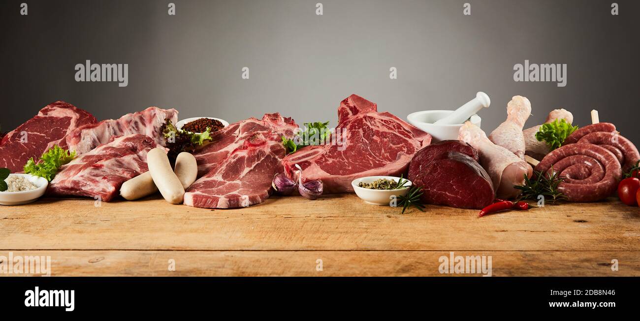 A selection of raw gourmet meats on a rustic timber chopping board with ...