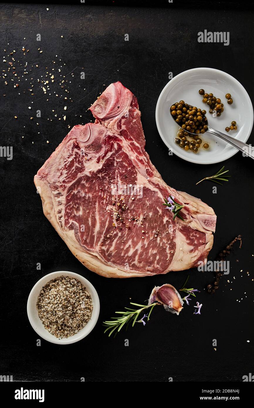Bone-in raw marbled pork steak with spice rub, fresh herbs and garlic ...