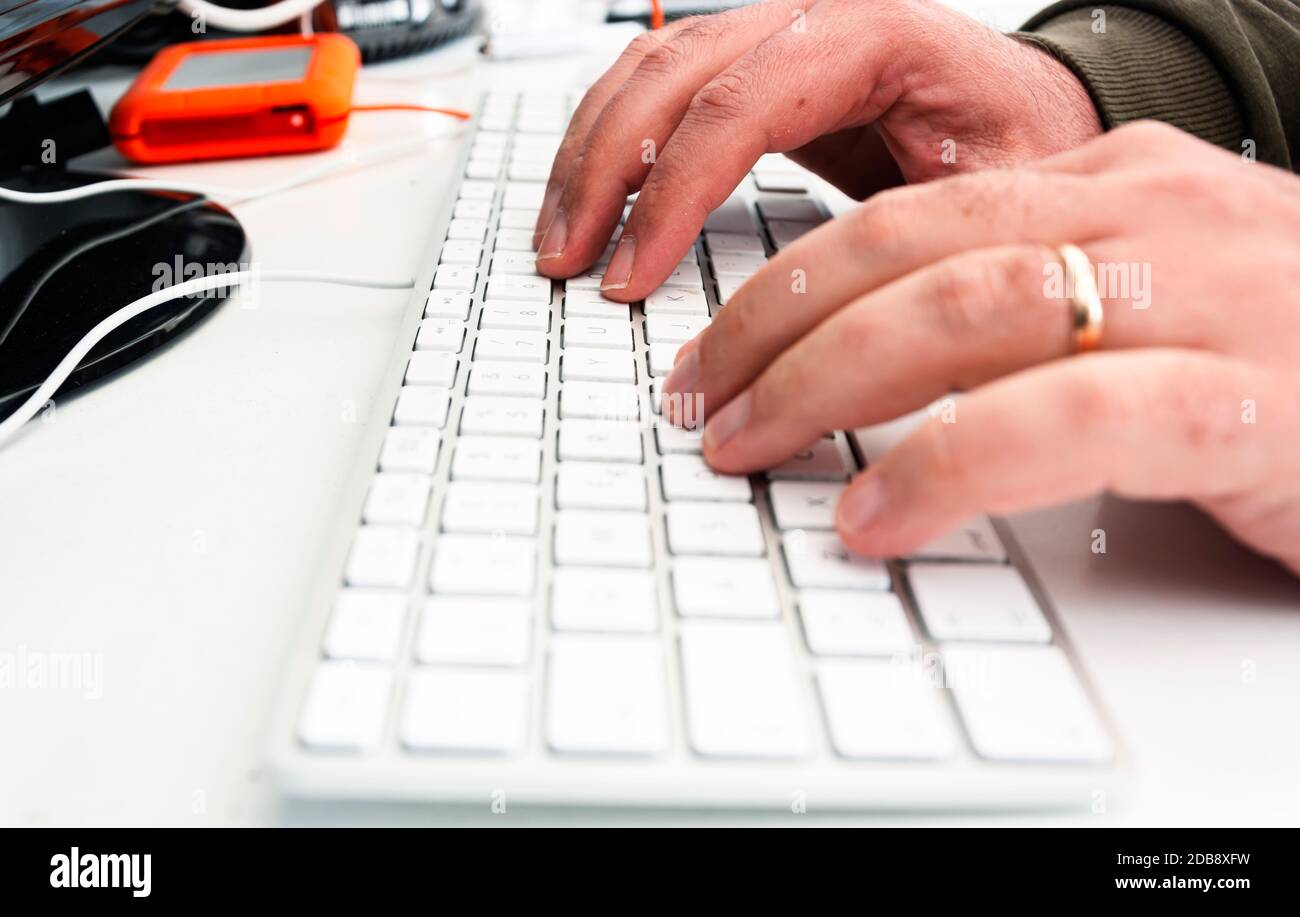 male hands typing keys on a white computer keyboard in an office ...