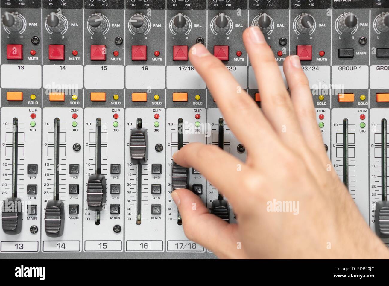 Close-up of a mixing console, hand equalizing audio channels ...