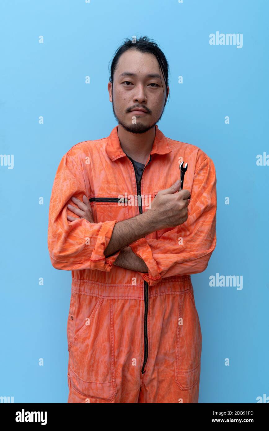 The chief mechanic in an orange uniform held a small wrench. Standing ...