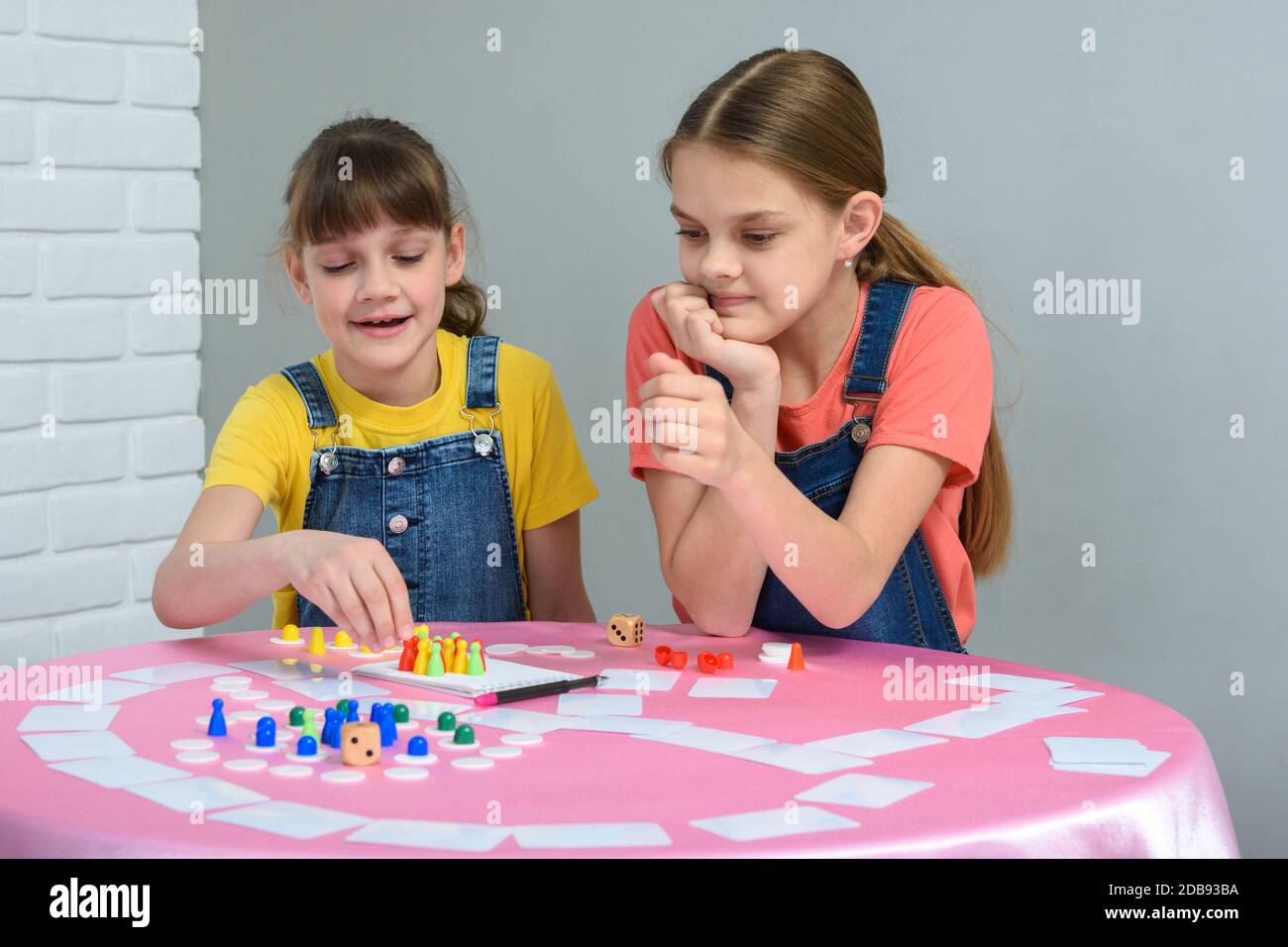 Two girls at the table play a board game Stock Photo - Alamy