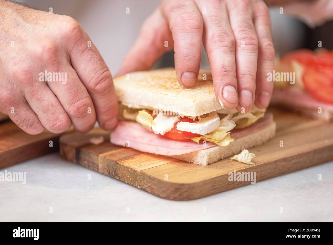 Chef making sandwich in rustic style with ham fresh vegetables and goat ...