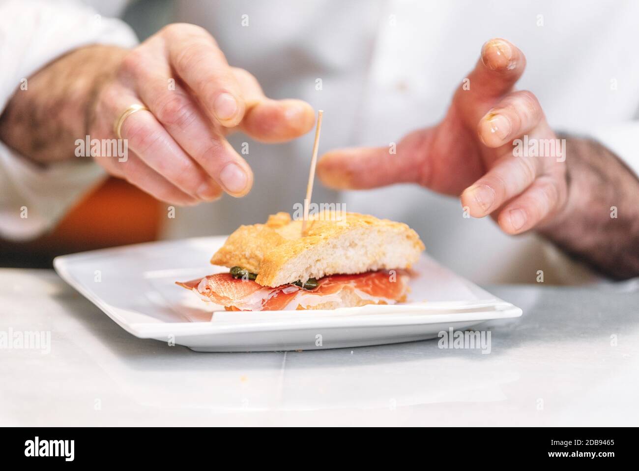 Chef preparing delicious typical Spanish food, ham tapa or Pintxo of ...