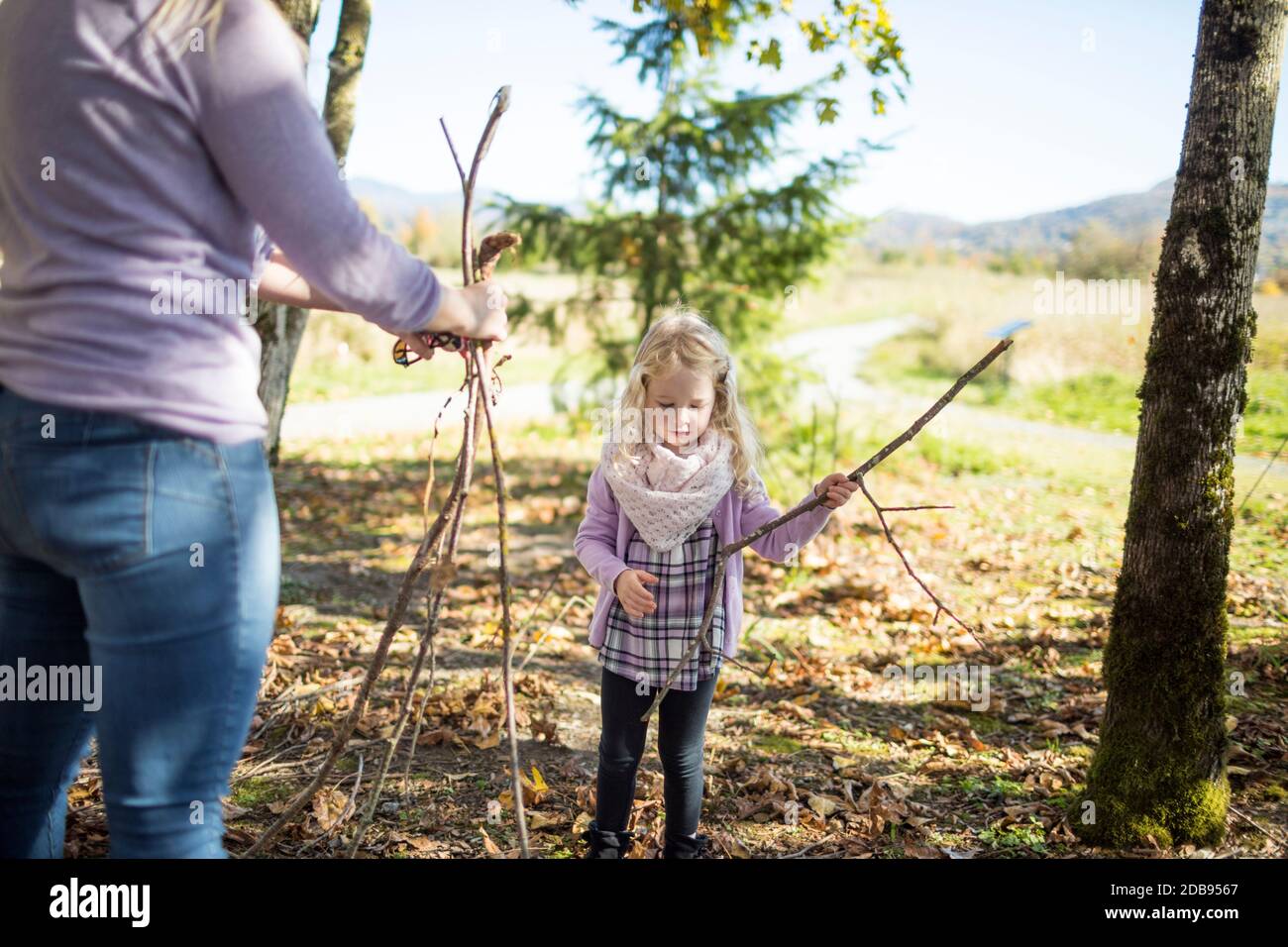 Mother and daughter build a small fort out of leaning sticks Stock ...