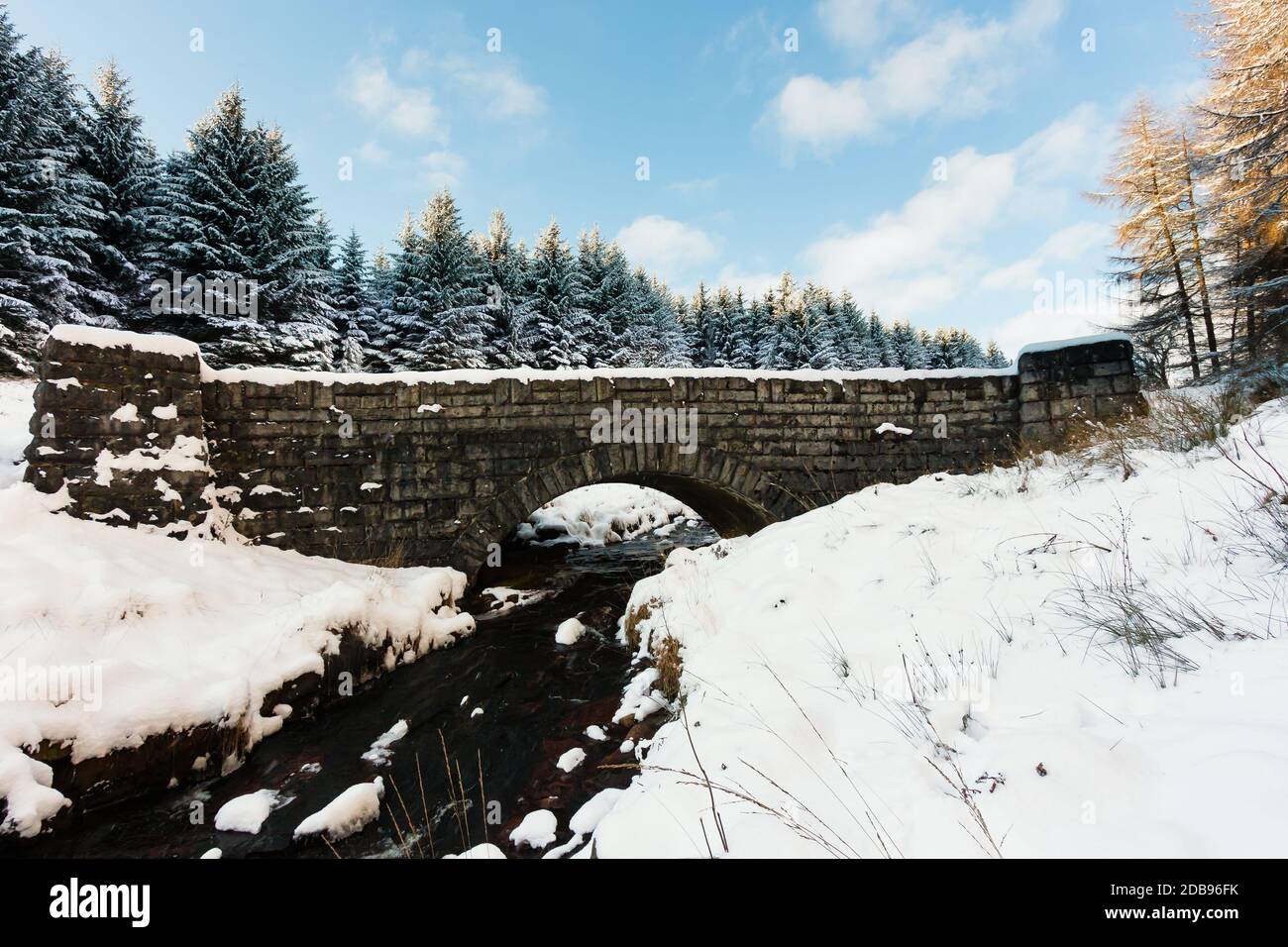 Small stone bridge over a stream in a snow covered forest landscape ...