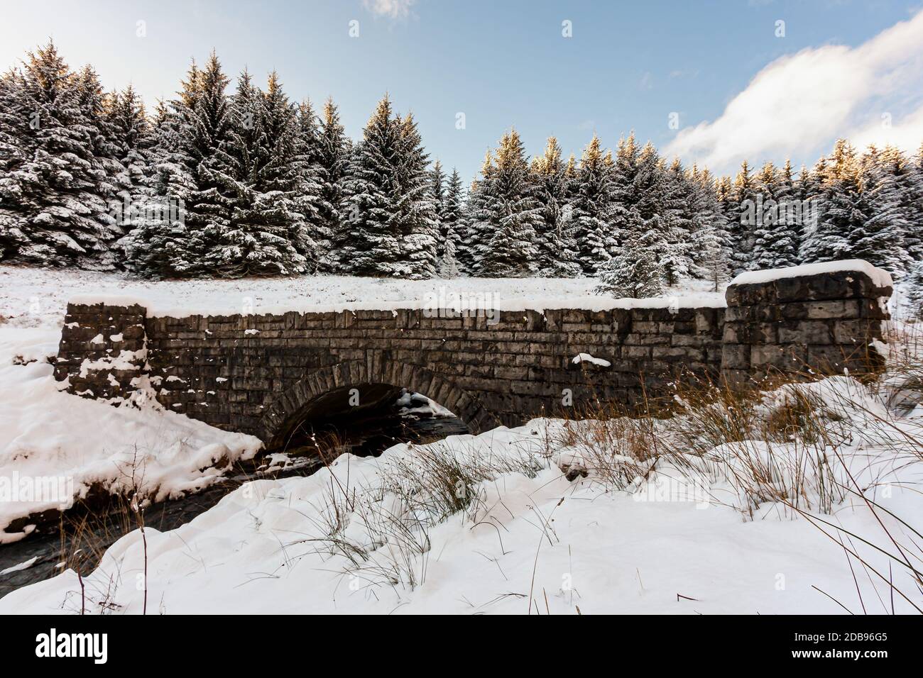 Small stone bridge over a stream in a snow covered forest landscape ...