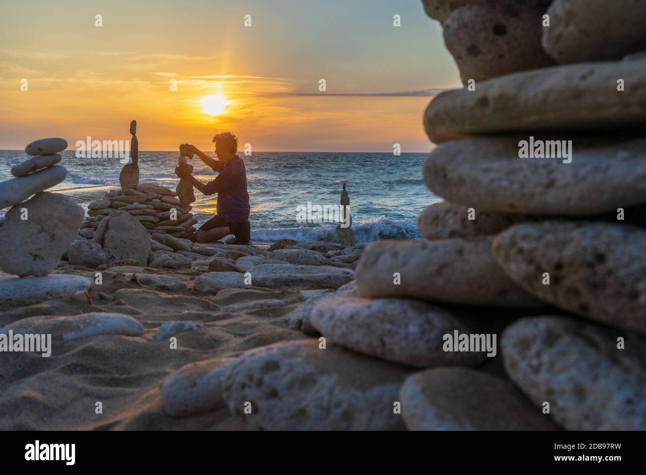Man stacking pebbles on beach Stock Photo - Alamy
