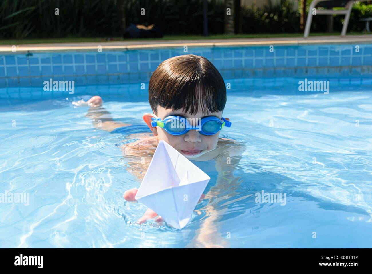 Child holding a paper boat in the pool on a summer day Stock Photo - Alamy
