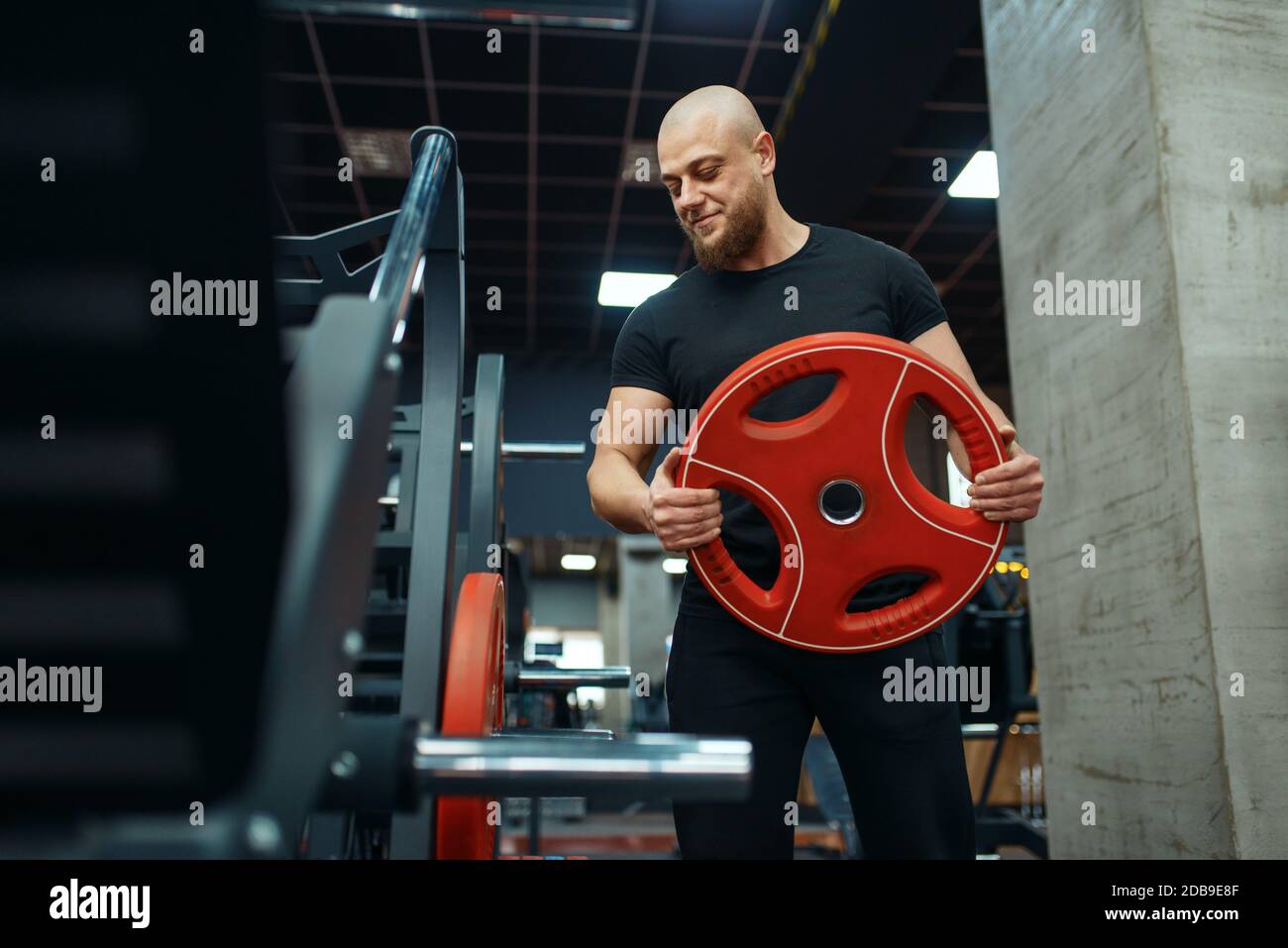 Bearded muscular man puts on weight on bar in gym. Male athletic ...