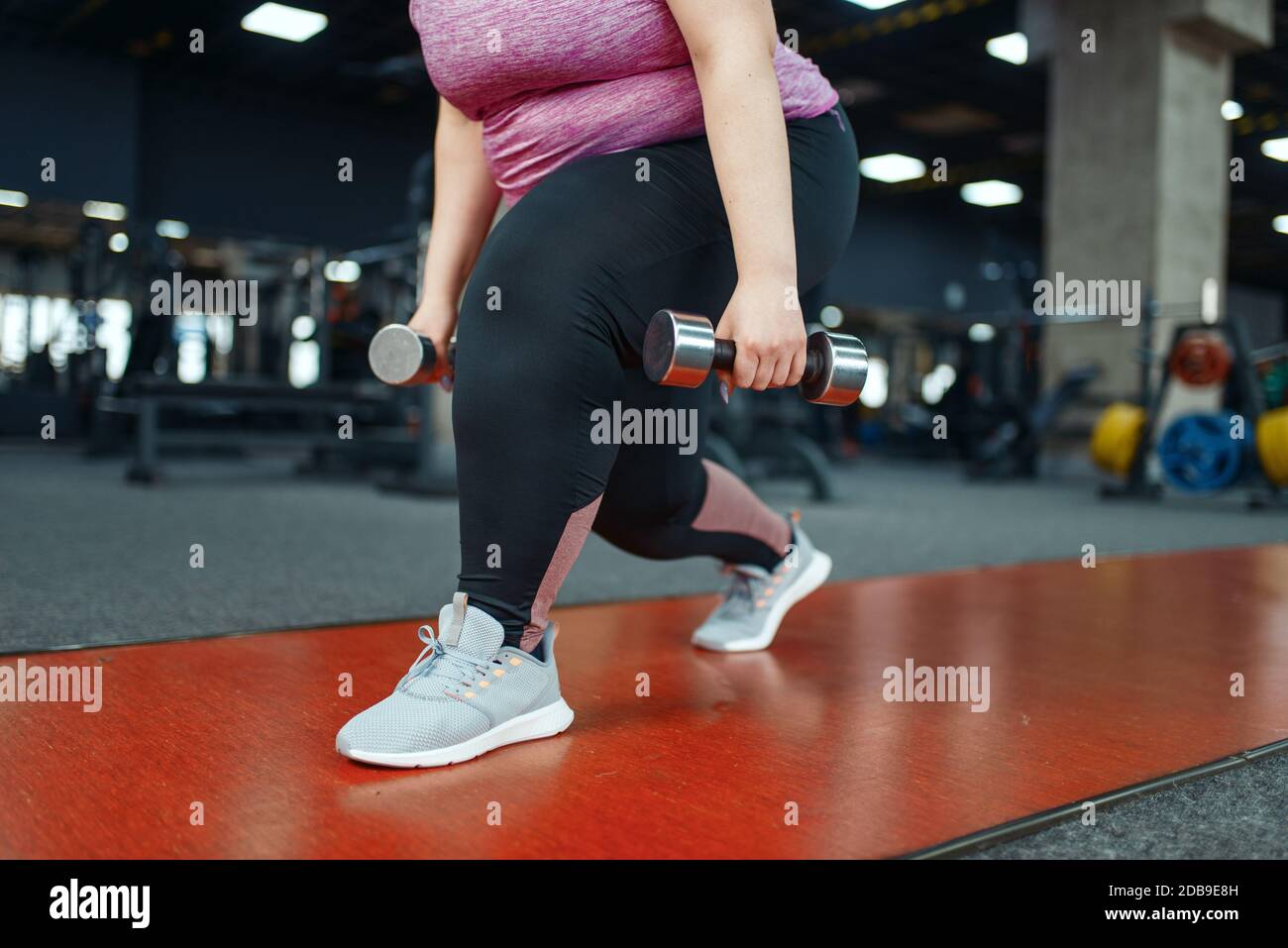 Overweight woman doing exercise with dumbbells in gym, active training ...