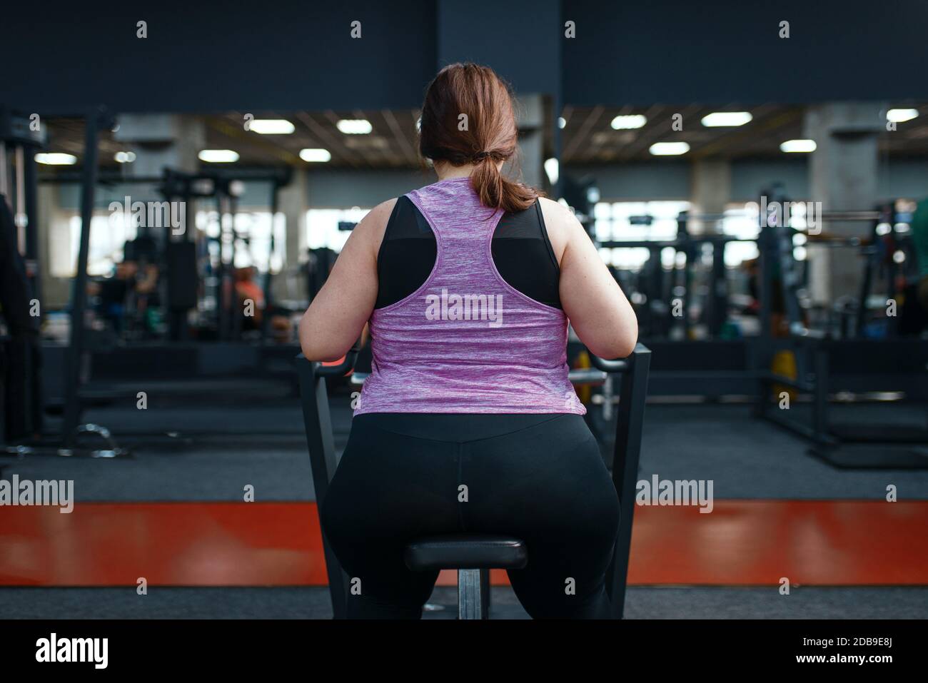 Overweight woman doing exercise in gym, back view, active training ...