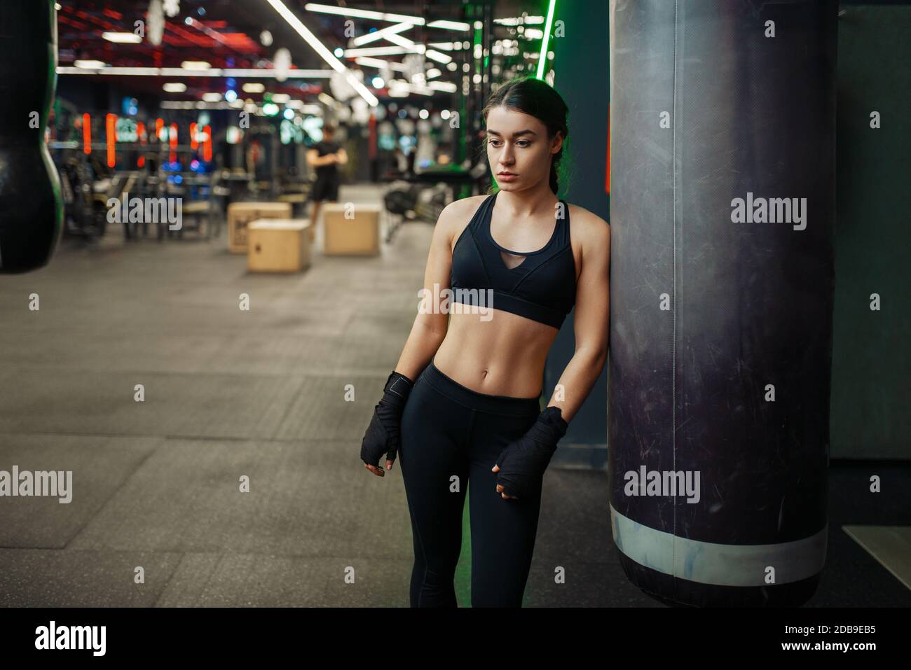Woman in black boxing bandages poses at the punching bag, box training ...