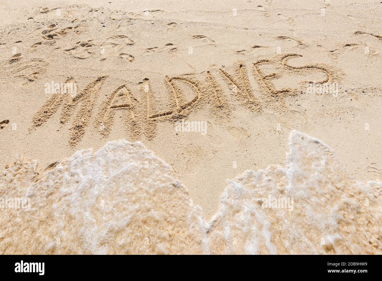 Handwriting word "Maldives" on maldivian beach drawn on sand and sea ...