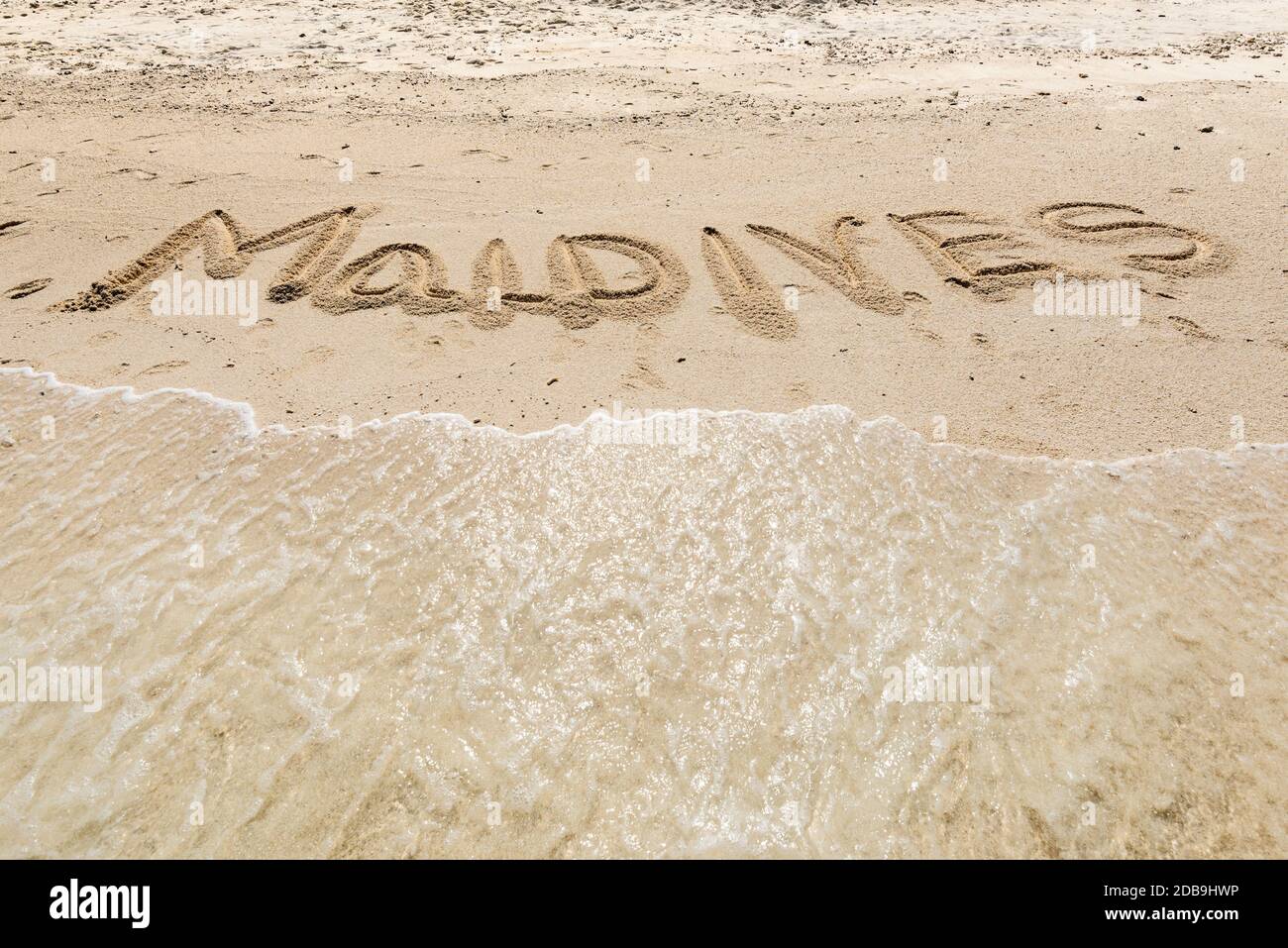 Handwriting word "Maldives" on maldivian beach drawn on sand and sea ...