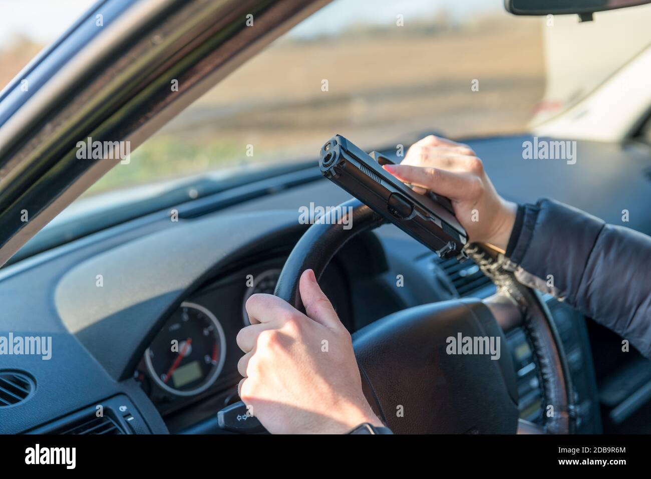 hands with gun on steering wheel of passenger car Stock Photo - Alamy