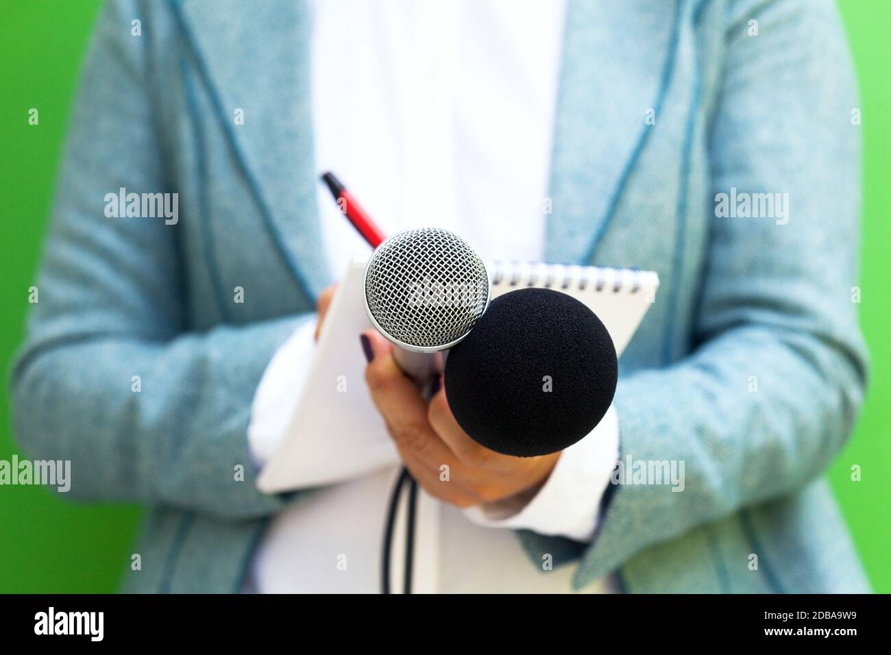 Female reporter at press conference, writing notes, holding microphone ...