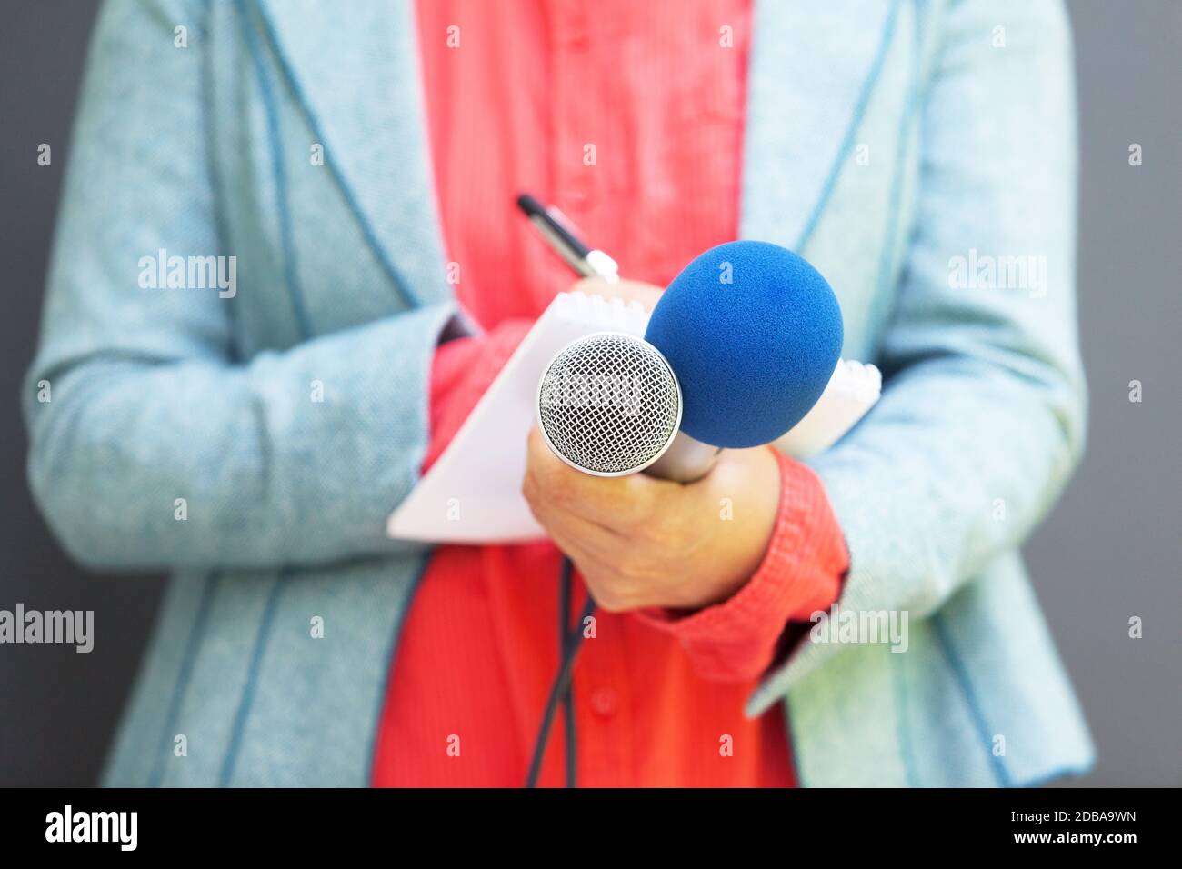 Female reporter at press conference, writing notes, holding microphone ...
