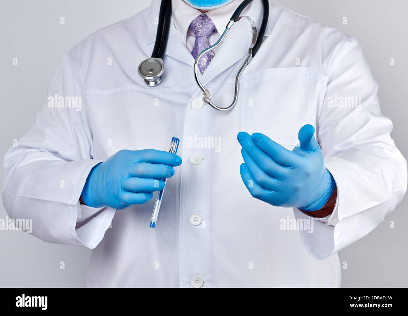 doctor in a white coat with buttons and blue latex gloves holds out his ...