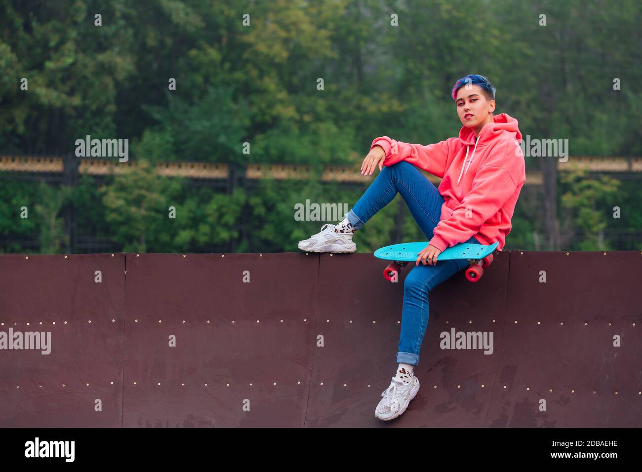 Portrait of a trendy pretty young gir with short colored hair sitting ...