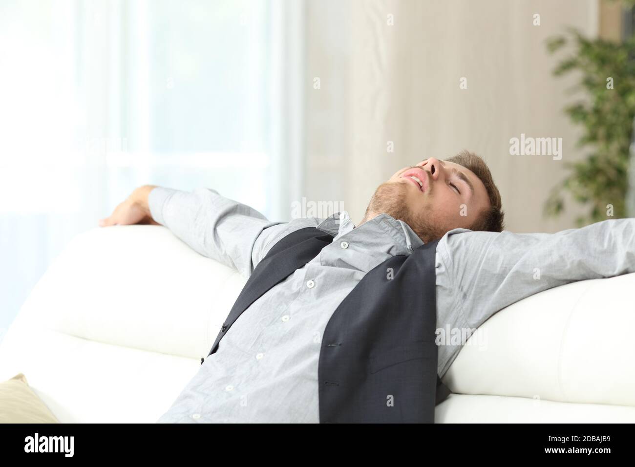 Tired executive man sleeping after hard work day sitting on a couch at ...