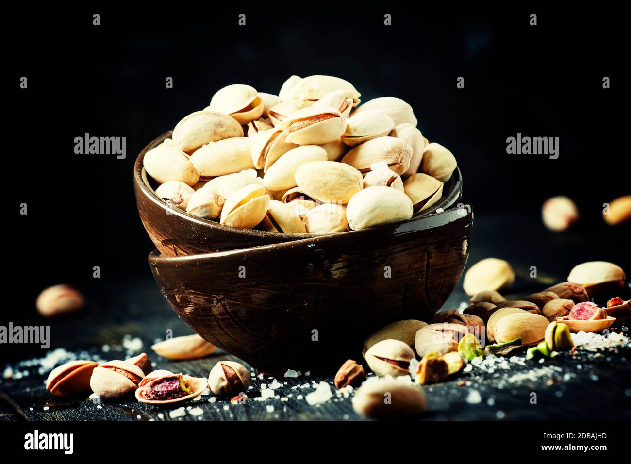 Salted pistachios in a bowl, black background, selective focus Stock Photo - Alamy