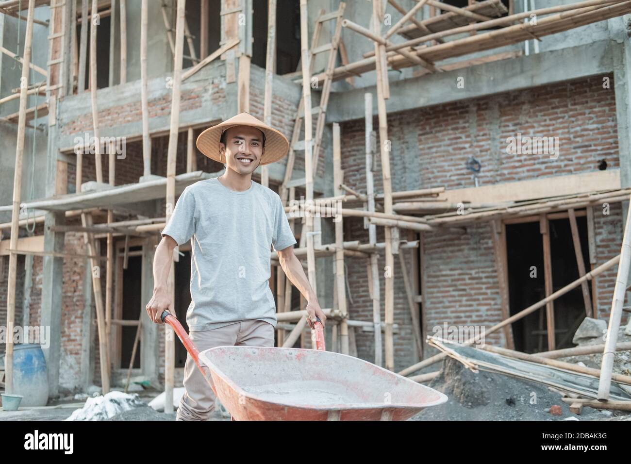 mason walking while pushing wheelbarrow with house building background ...