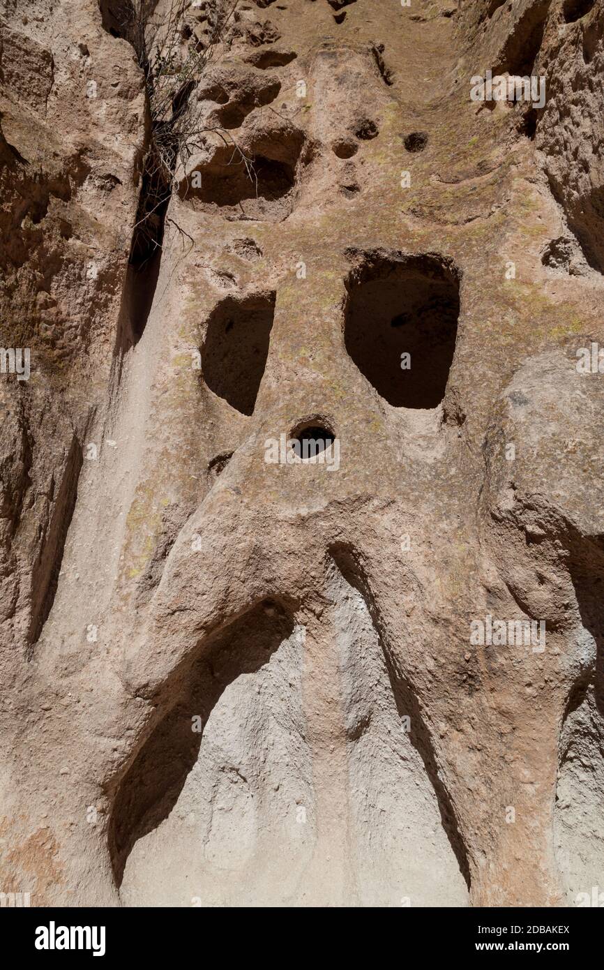 An eroded sandstone cliff with cave openings that look like a scary ...