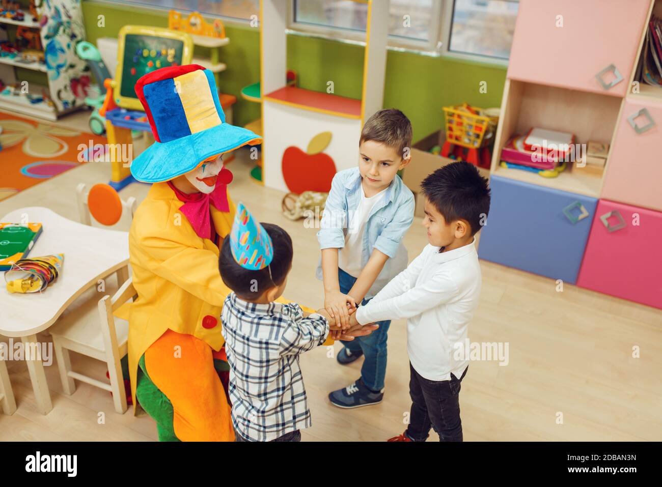 Funny clown with cheerful children play counting game together ...