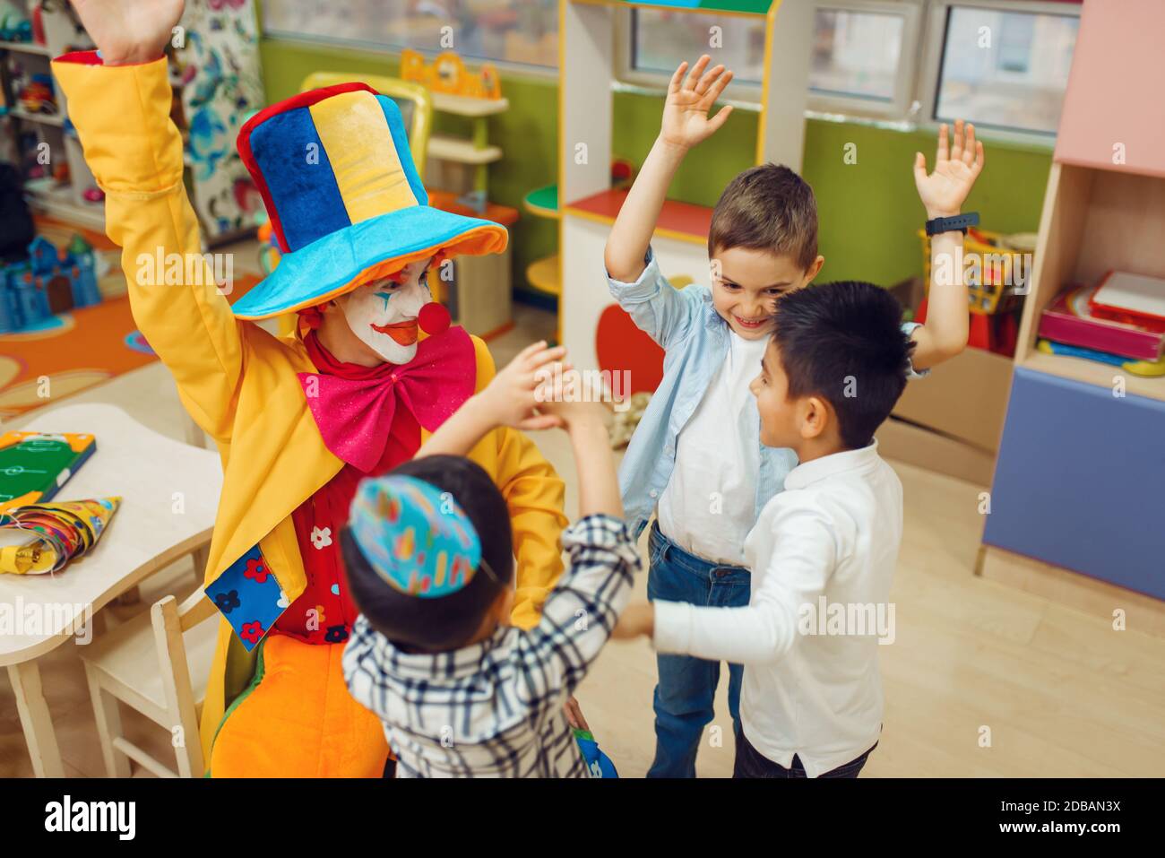 Funny clown with cheerful children play counting game together ...
