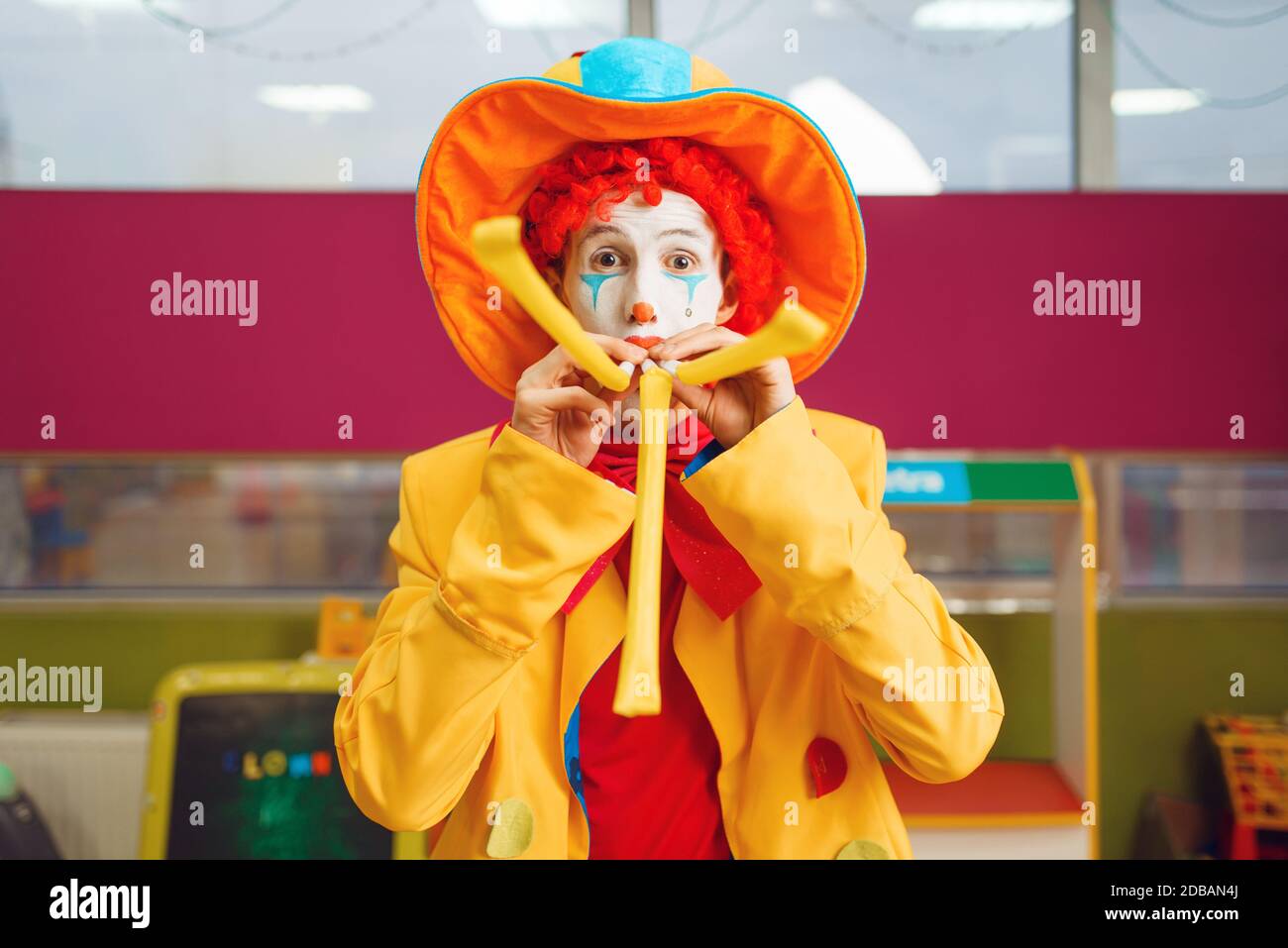 Funny clown with makeup blows into the party whistle tube. Birthday ...
