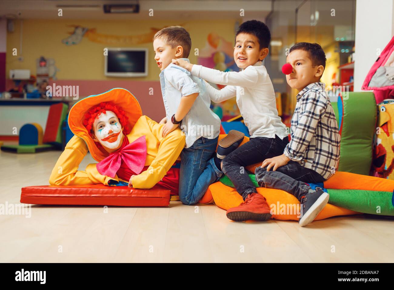 Joyful little boys sitting on funny clown in children's area. Birthday ...
