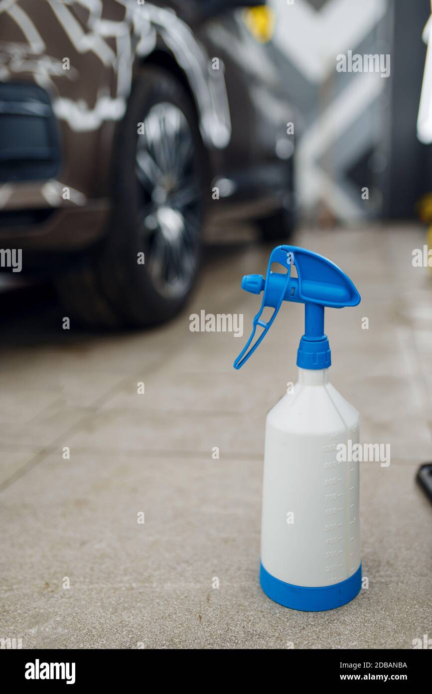 Bottle with spray gun, car with protection film on background, nobody ...