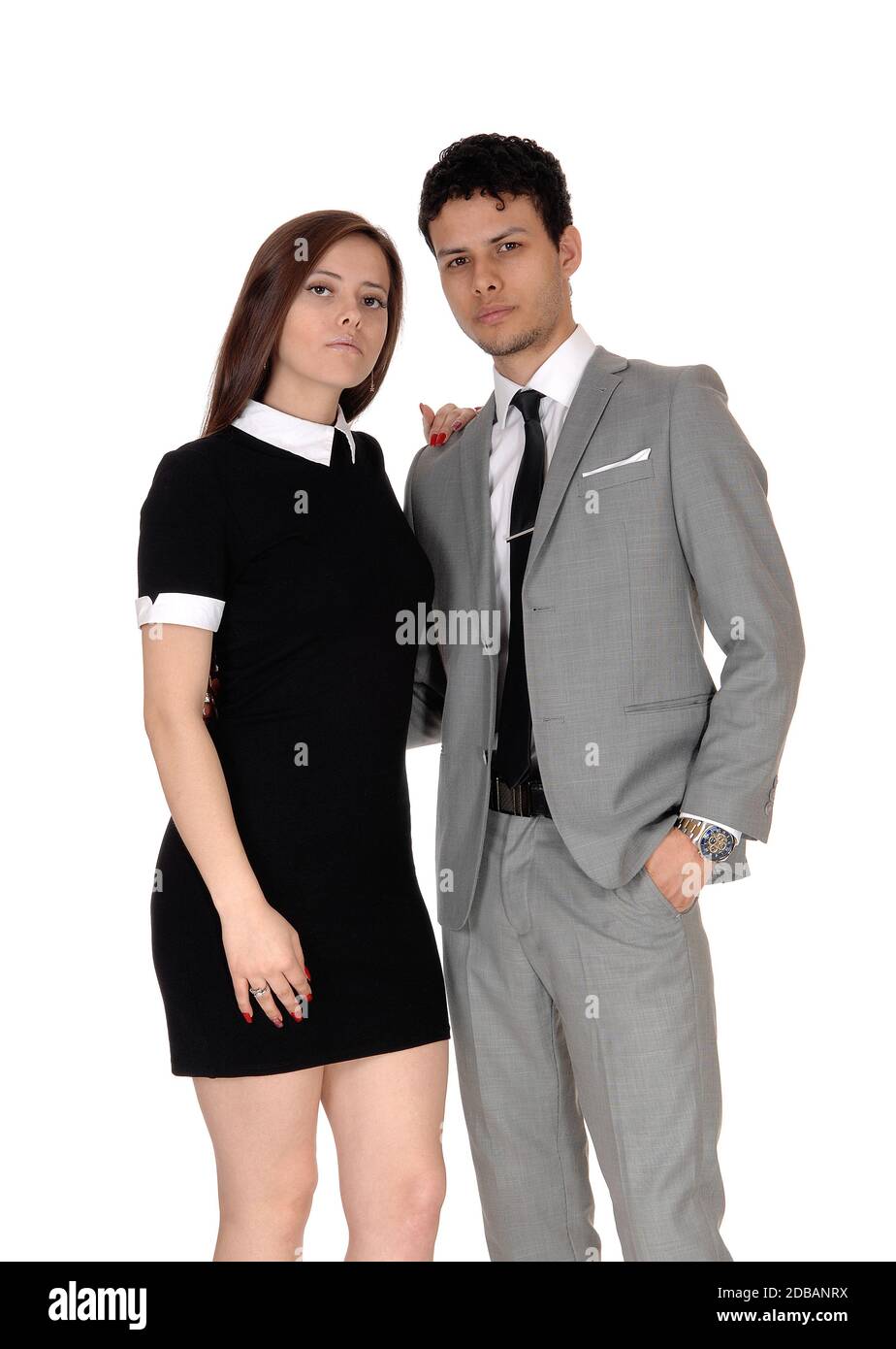 A happy young couple in suit and dress standing serious looking in the ...